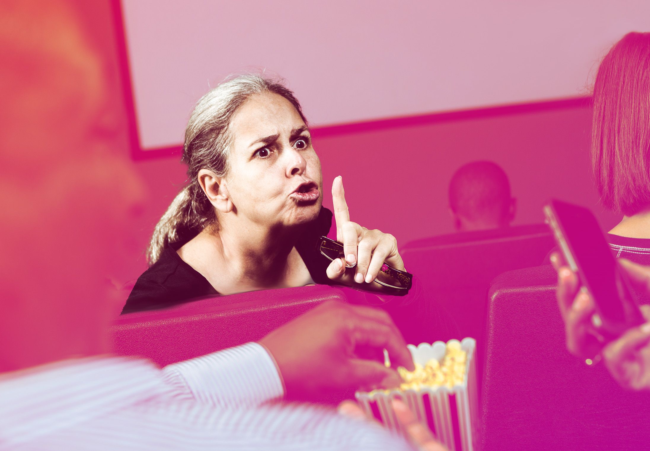A woman shushing the person behind her at a movie theater, graded in Polygon pink