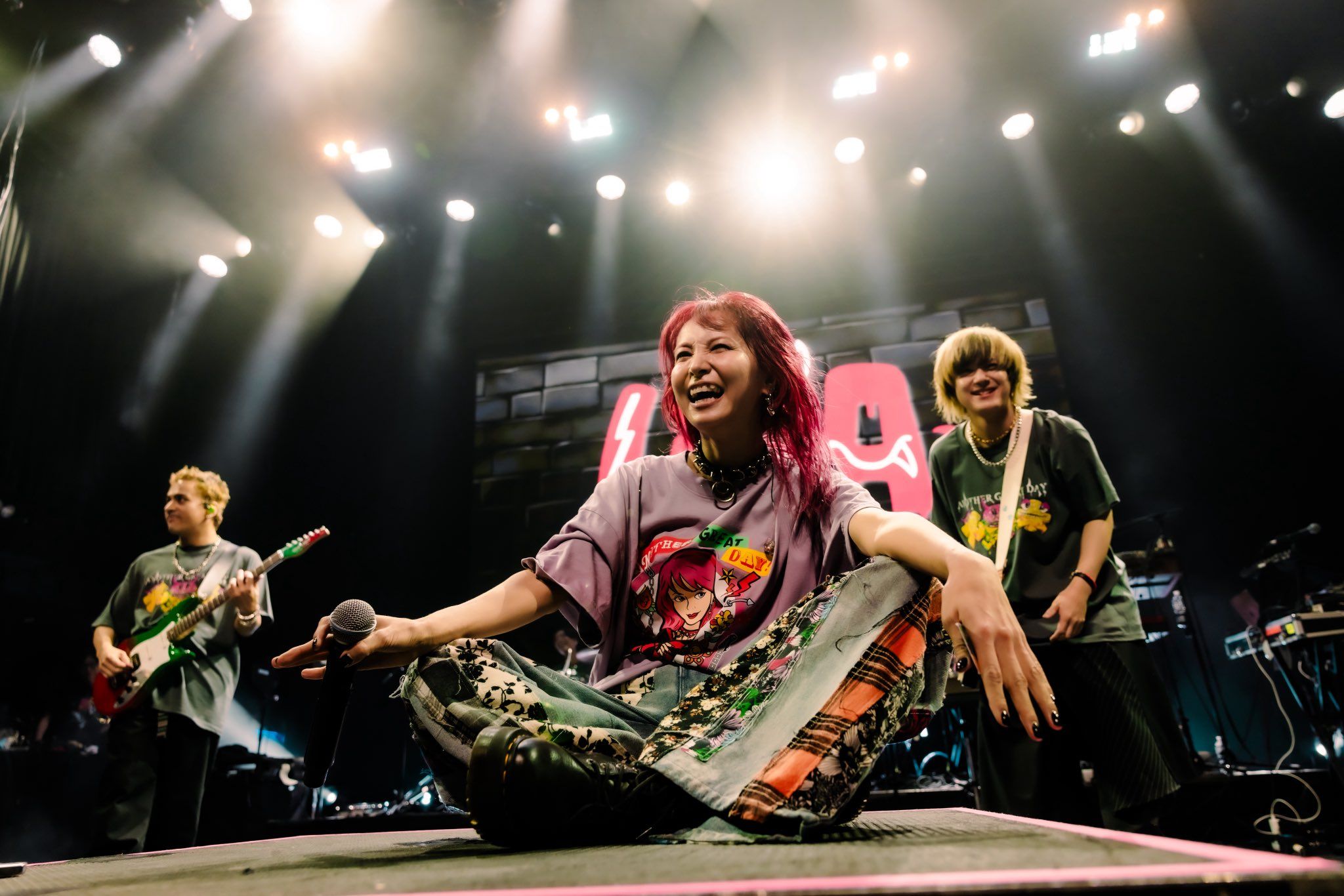 a woman sits on stage flanked by her guitarist and bassist at a show in New York City’s Terminal 5