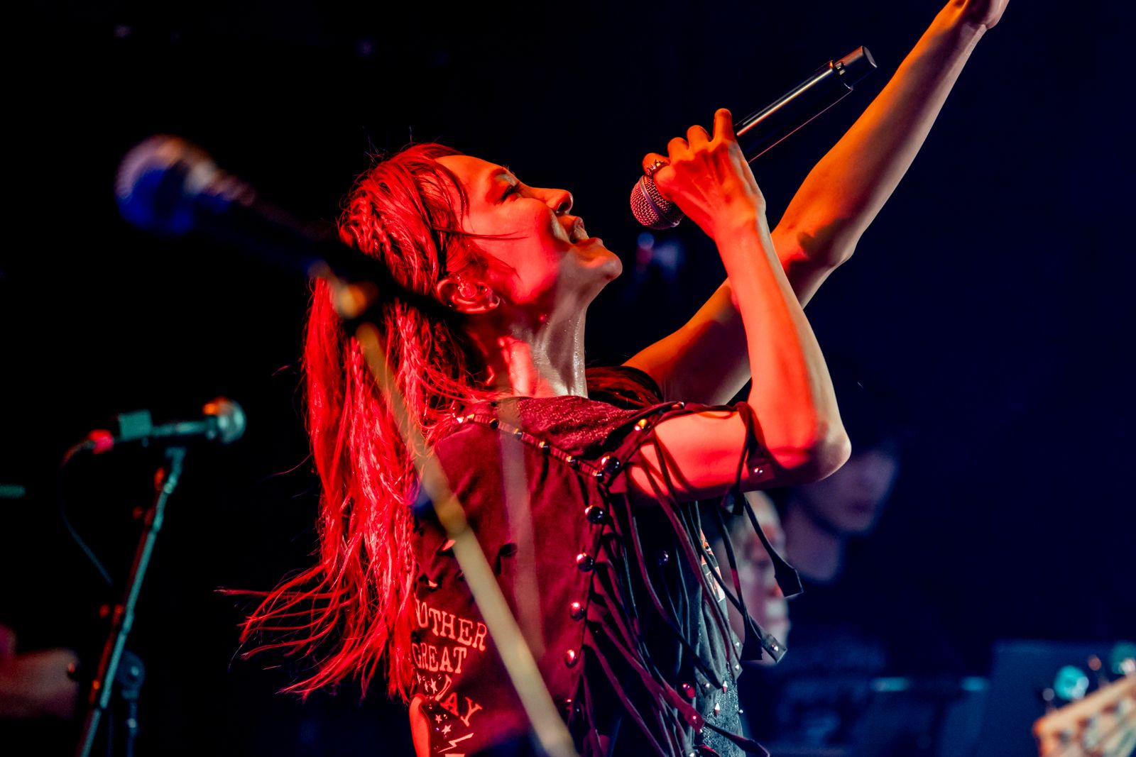 A woman, j-pop musician named LiSA, on stage singing into a microphone