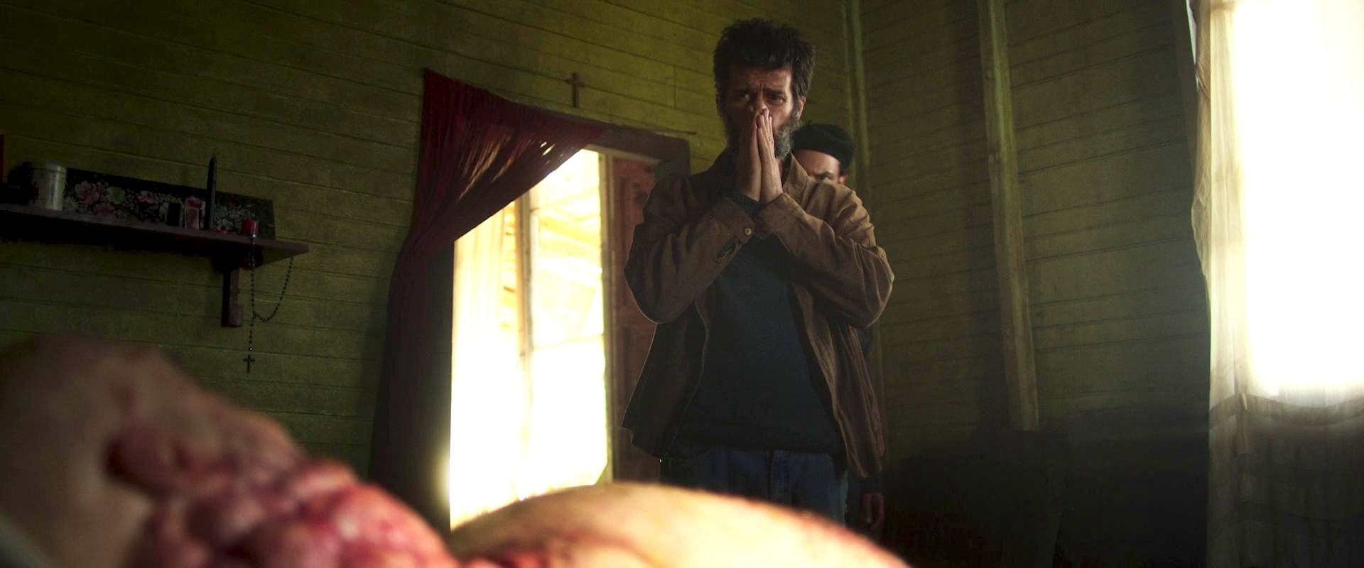 A man gasps as he looks at a bloated corpse that’s mostly off screen in When Evil Lurks
