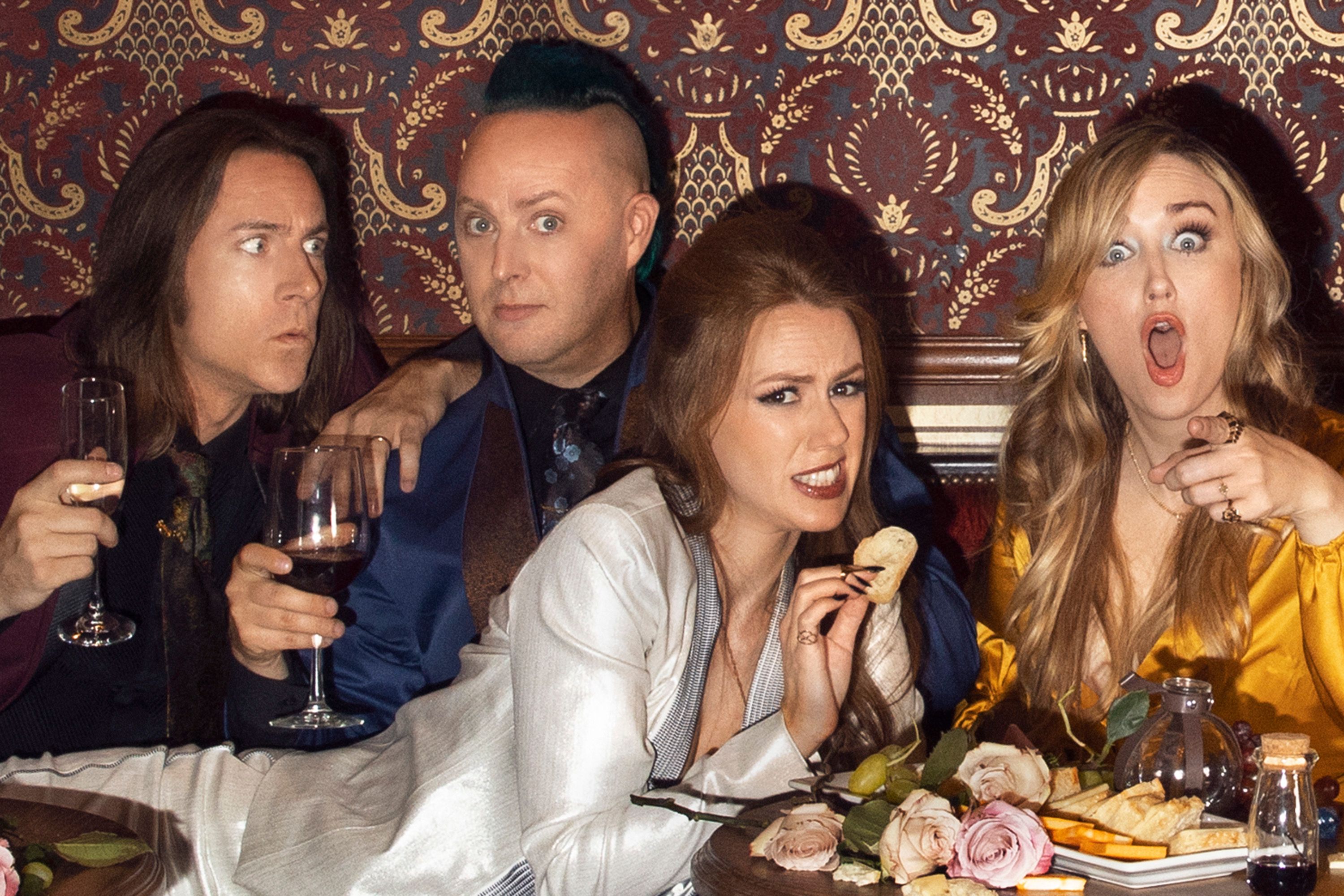The gang from Critical Role, including Mercer, look aghast during a photo shoot at a fancy restaurant.